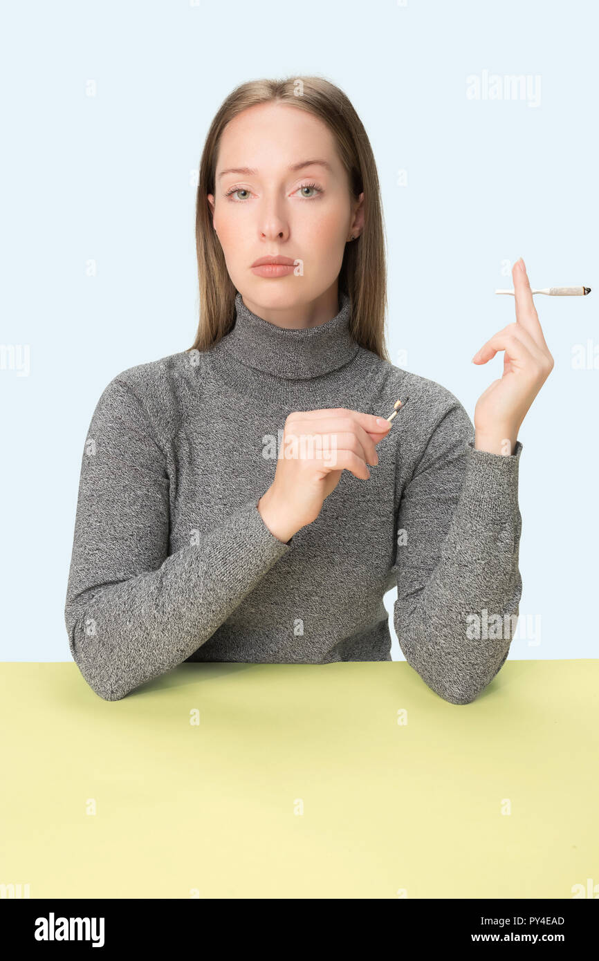 The young woman smoking cigarette while sitting at table at studio ...