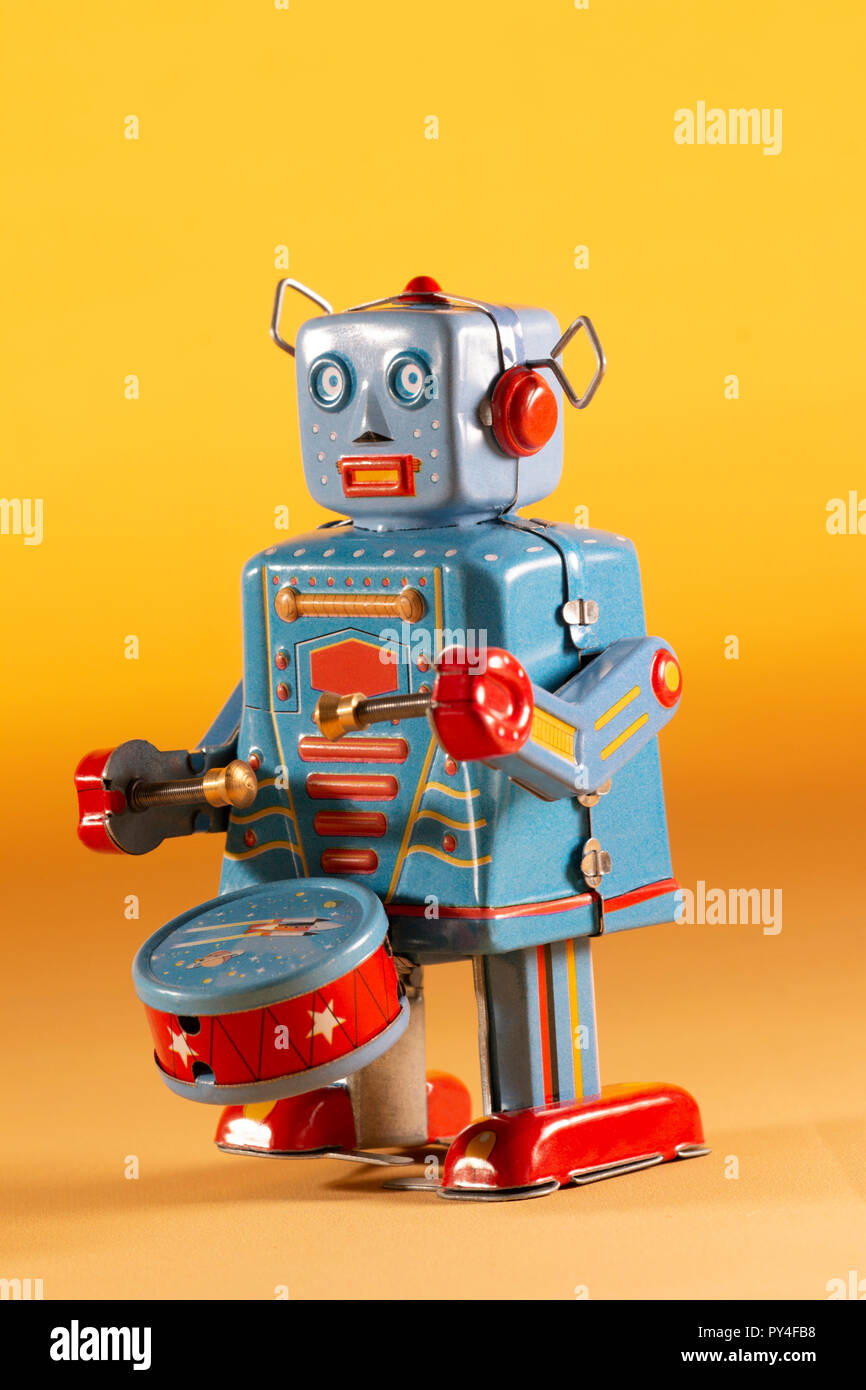 Vintage tin robot toy isolated on a yellow background Stock Photo - Alamy