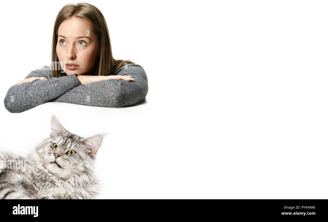 The funny sad woman and her cat looking serious over white background ...