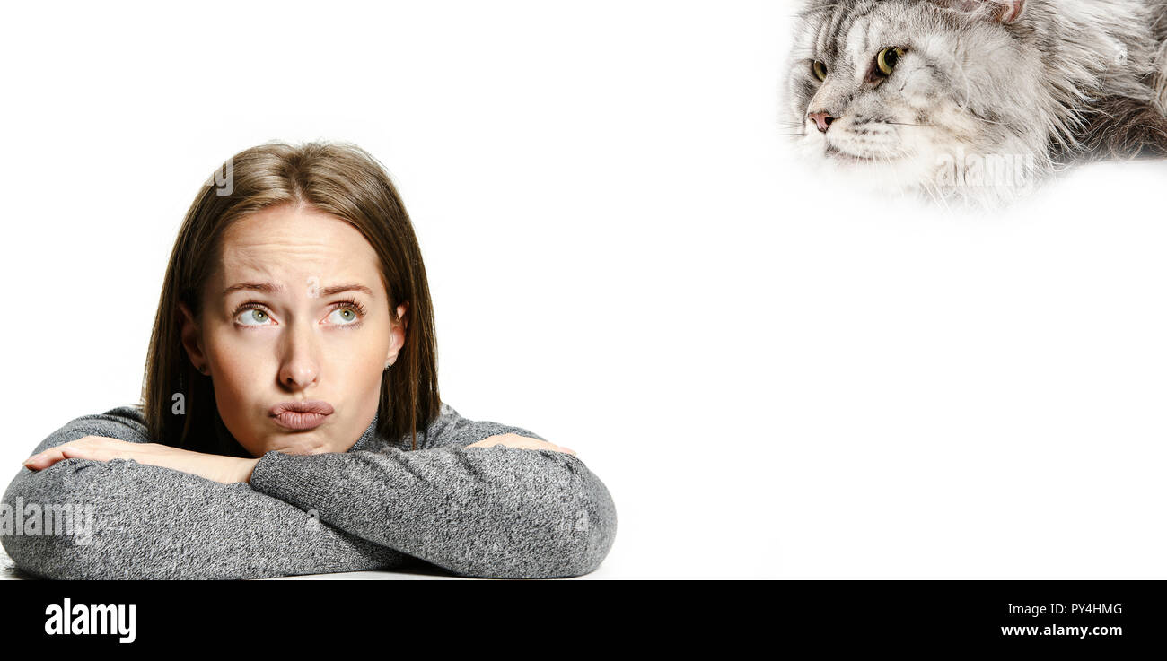 The funny sad and bored woman and her cat looking serious over white ...