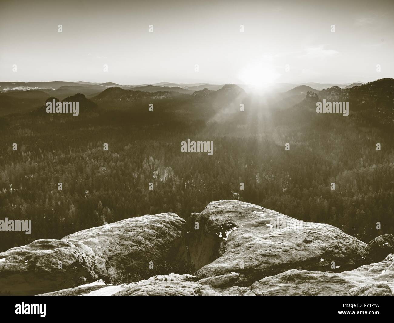 Exposed sandstone cliff above deep misty valley at beginning of hot ...