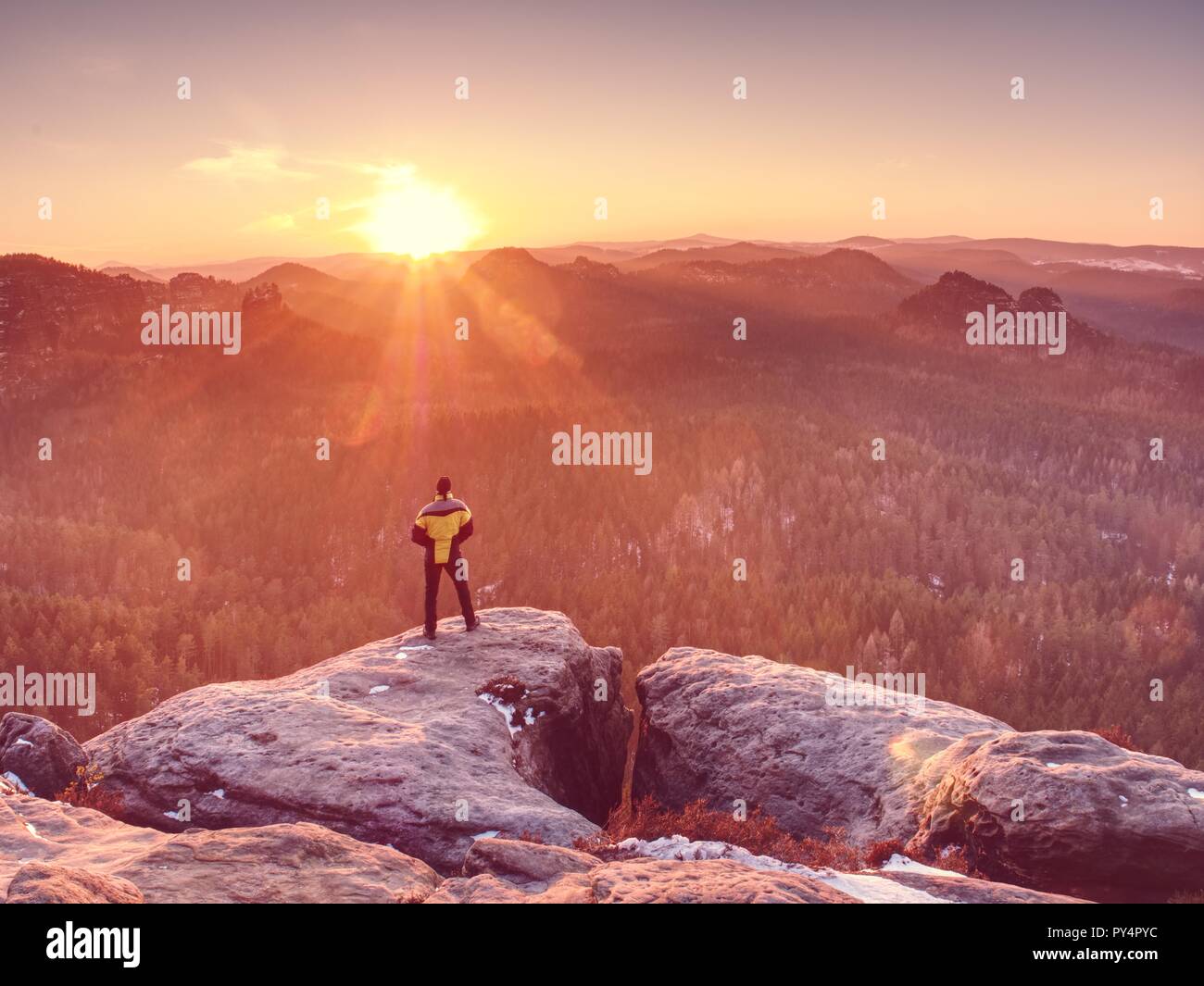 Man standing at the rocky edge. Young man watching sunrise at hilly ...