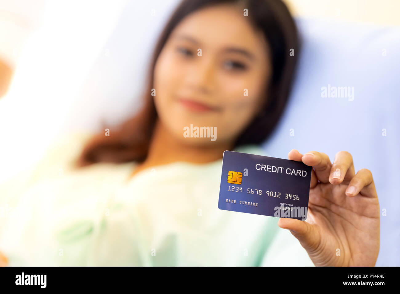 Portrait of Young adult female Patient with credit card in bed of ...