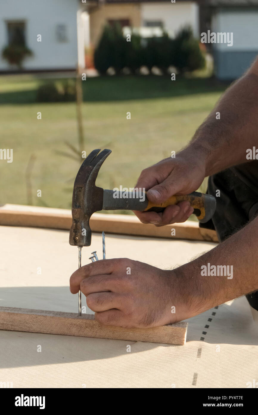 Roof construction building. Man hammering nails in to construction ...