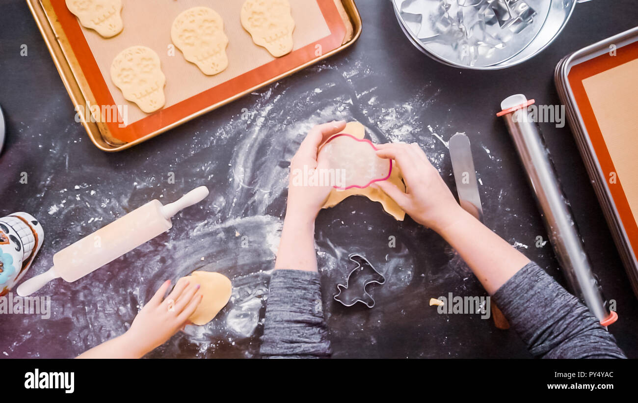 Flat lay. Mother and daughter baking sugar skull cookies for Dia de los ...