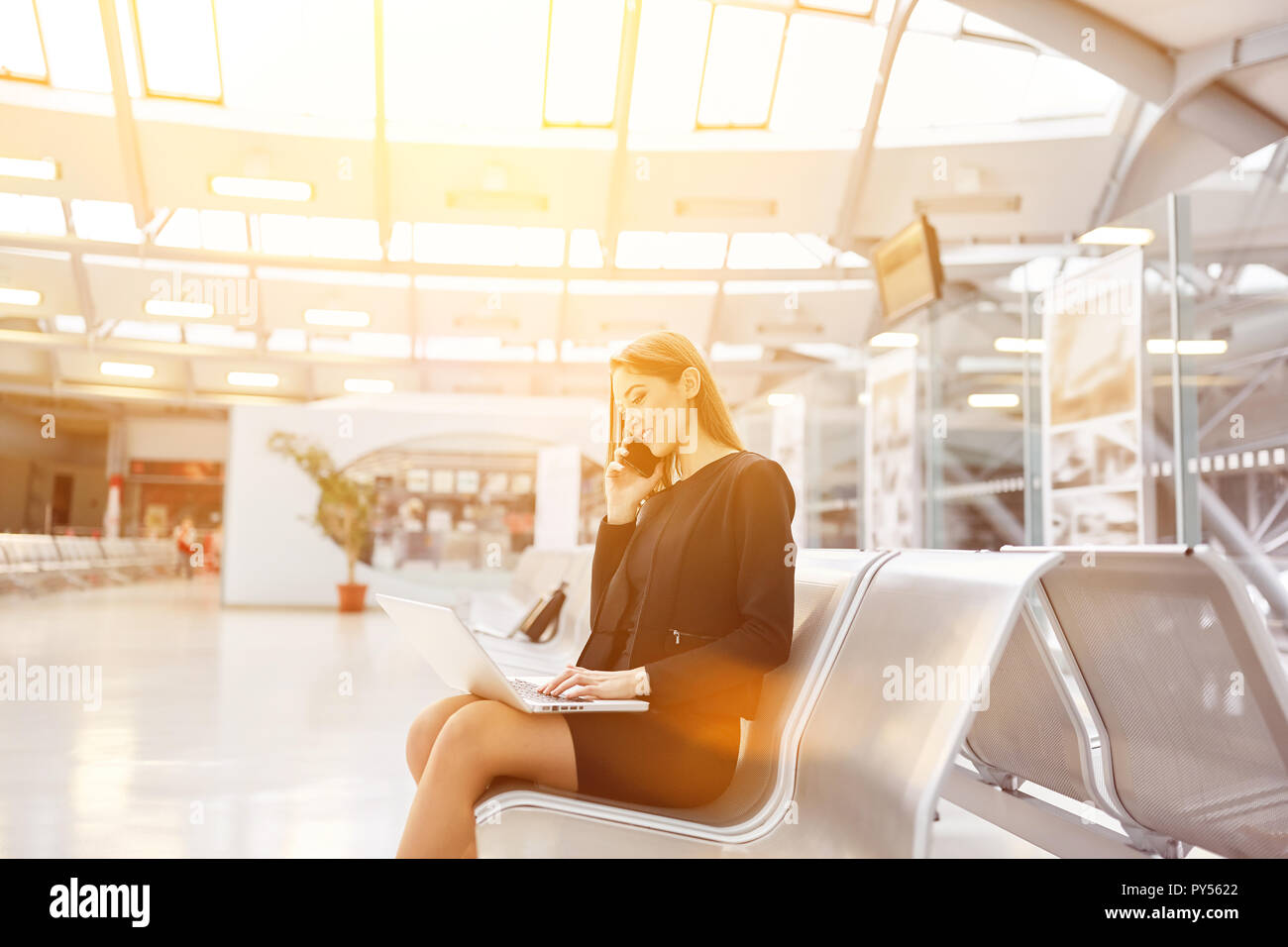 Businesswoman works with laptop computer and smartphone at airport ...