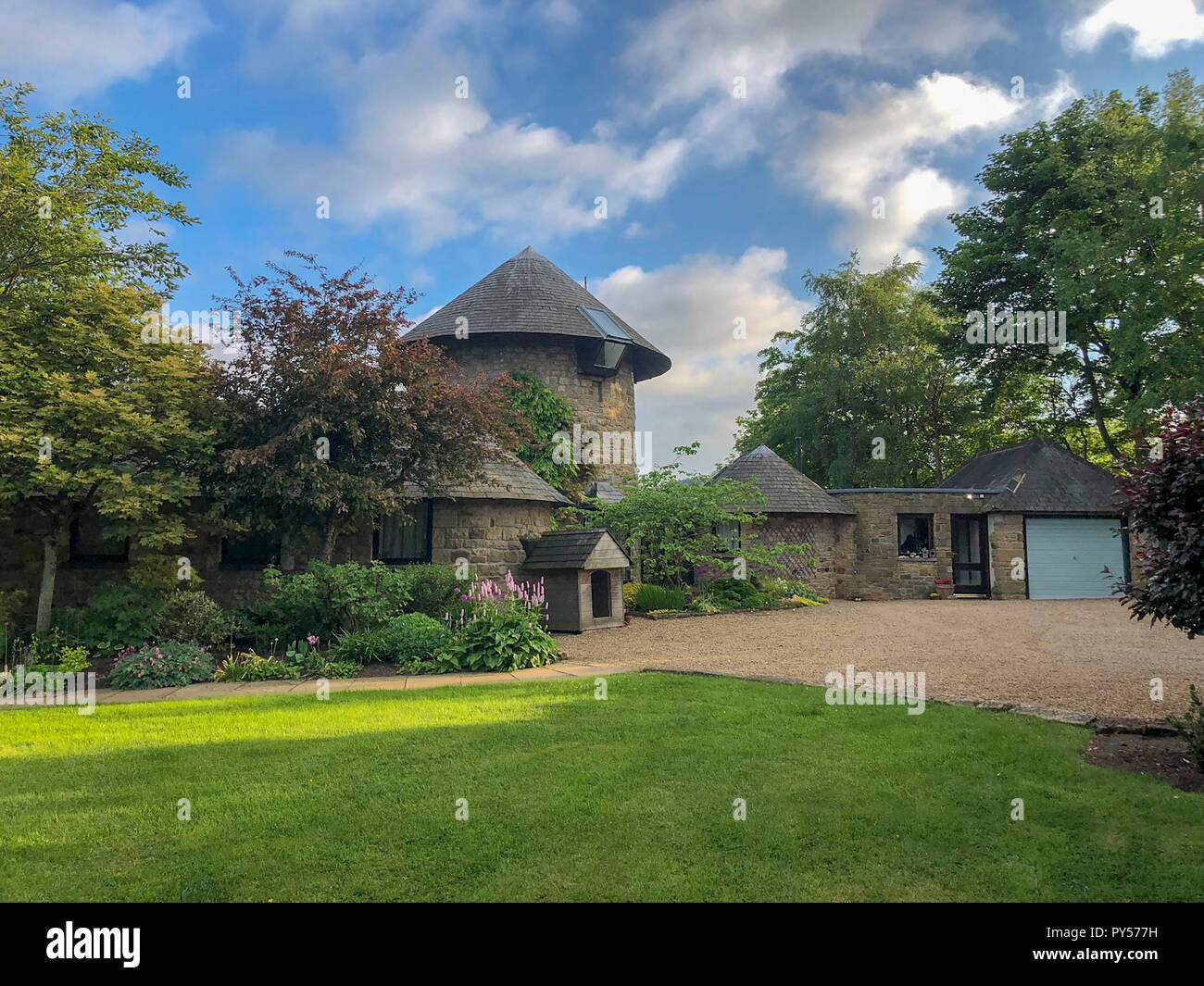 A wide view shot of a large stone house on a cloudy day, the garden is ...