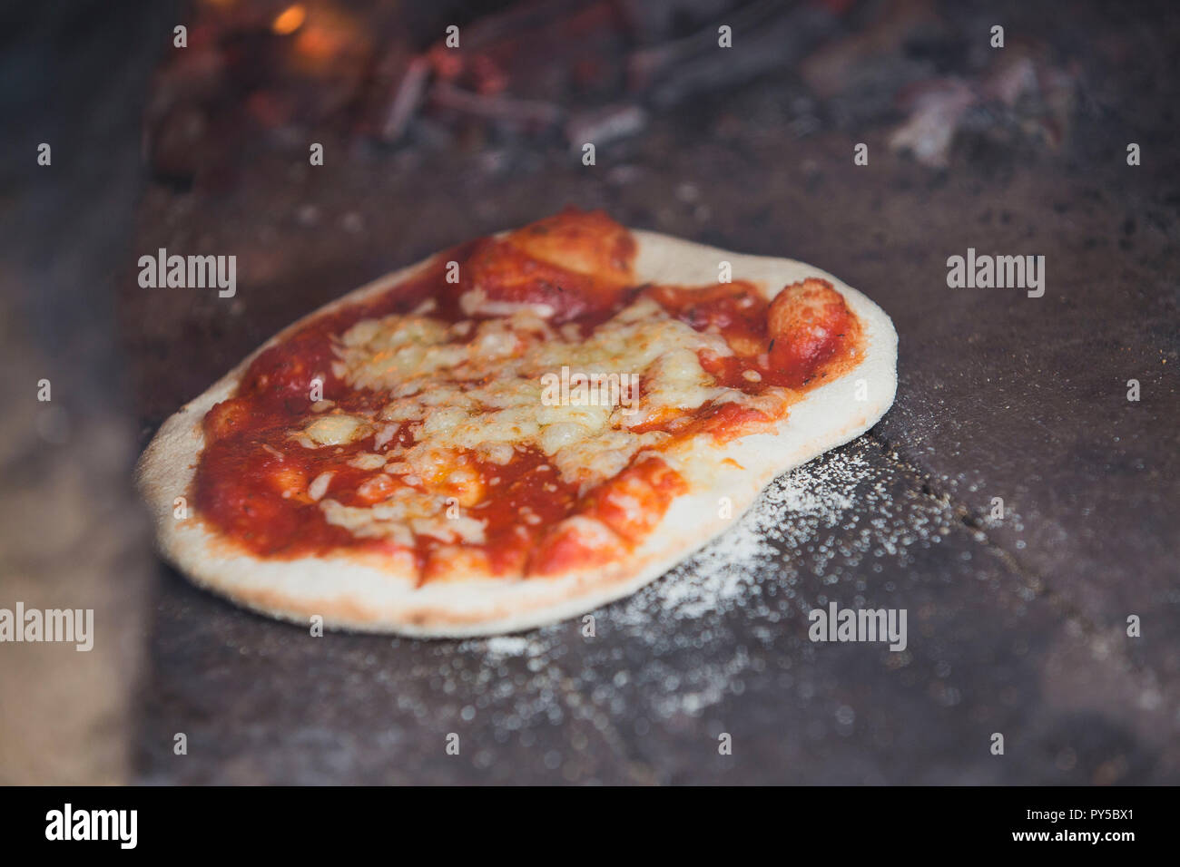 Handmade pizza being cooked on a home made outdoor pizza over in ...