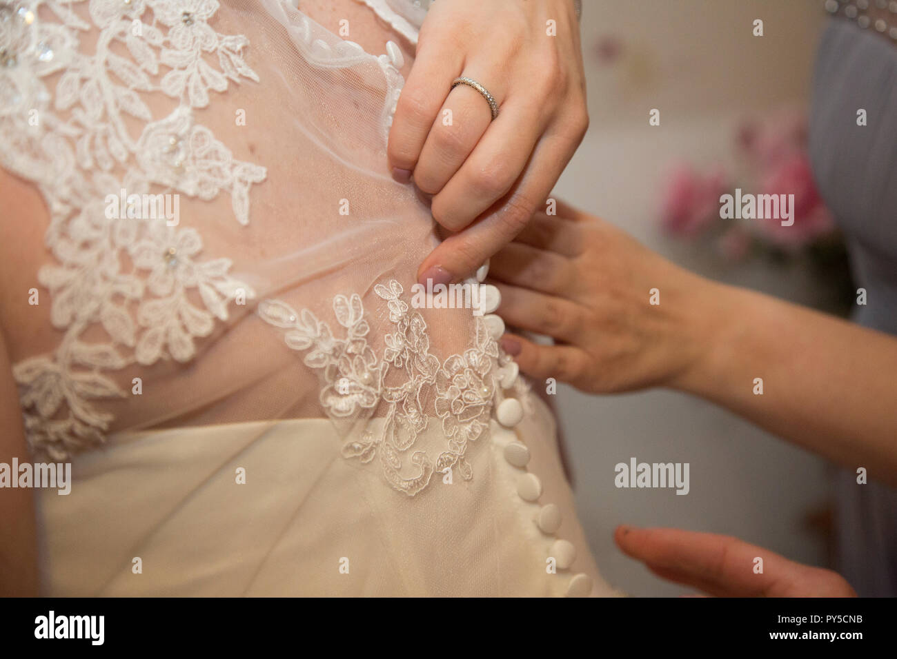 close up of the Bride having her dress done up before she gets married ...