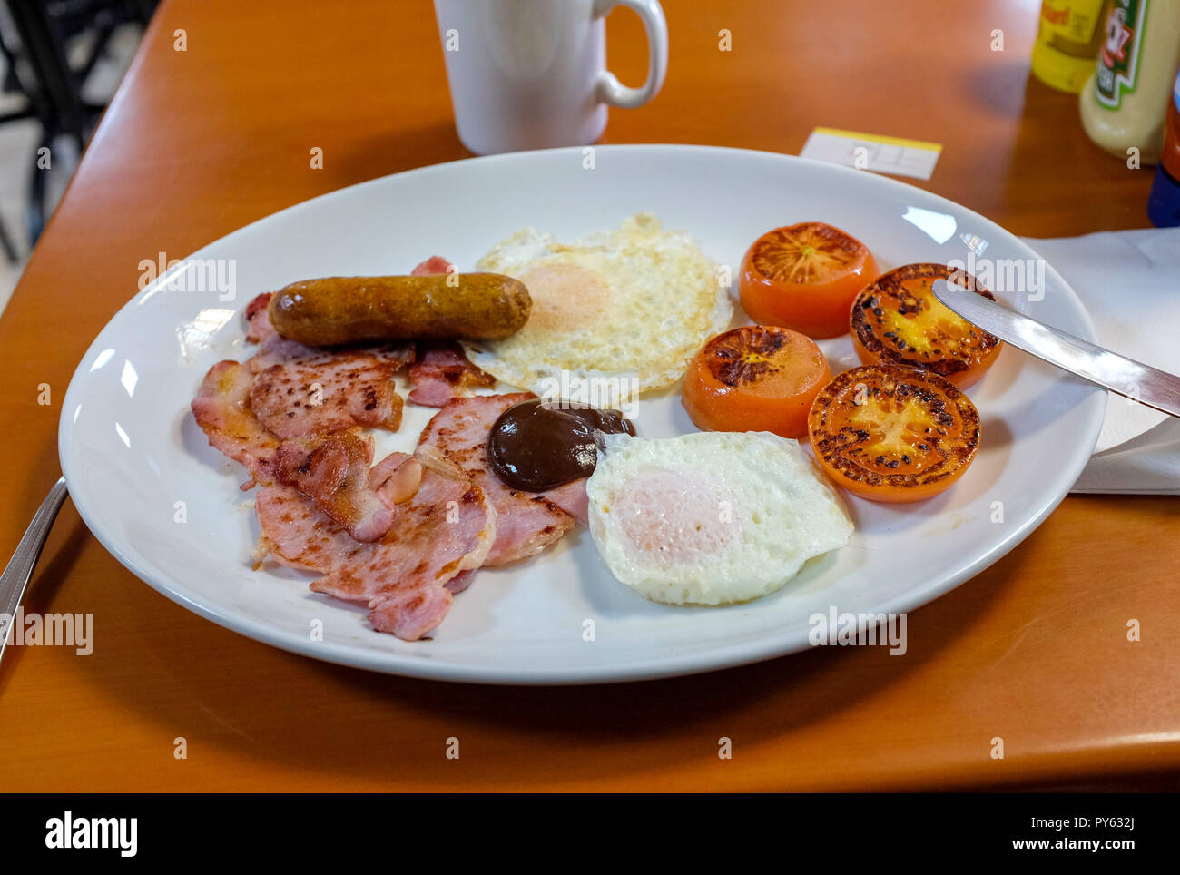 Typical traditional English breakfast of sausage bacon fried eggs and ...