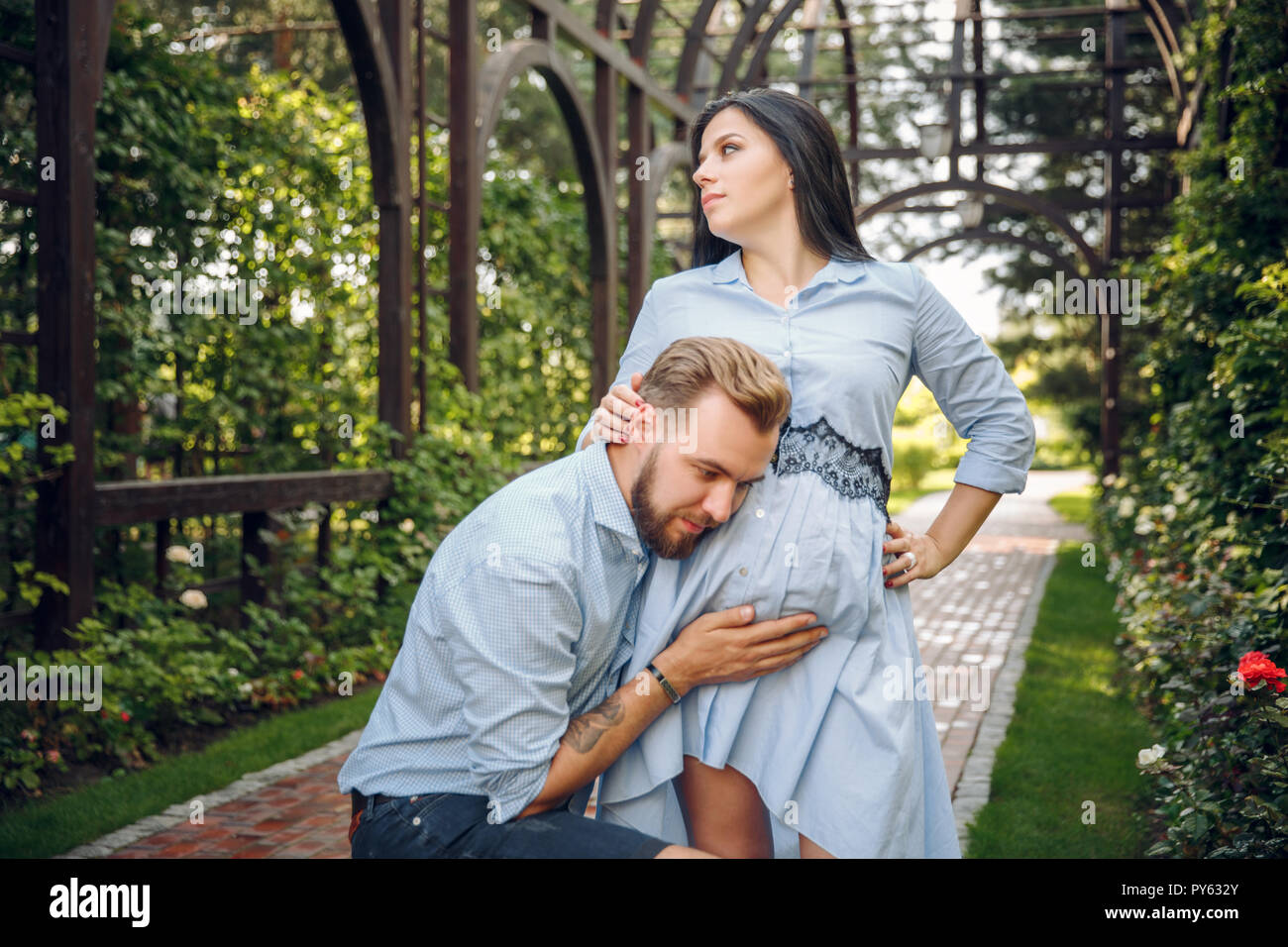 young couple pregnant in the spring in the flowered garden, a man ...