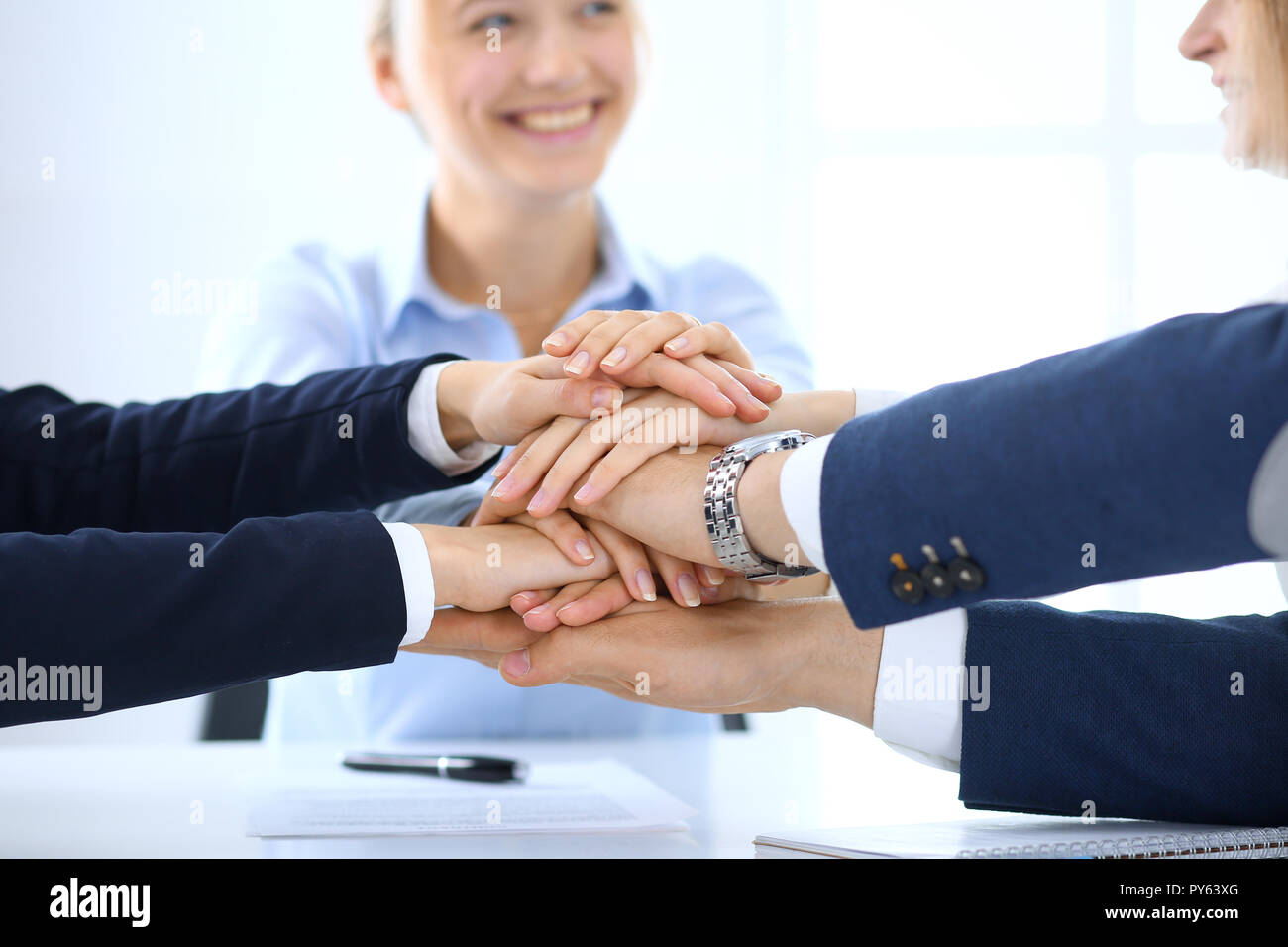 Business team showing unity with their hands together. Group of people joining hands and ...