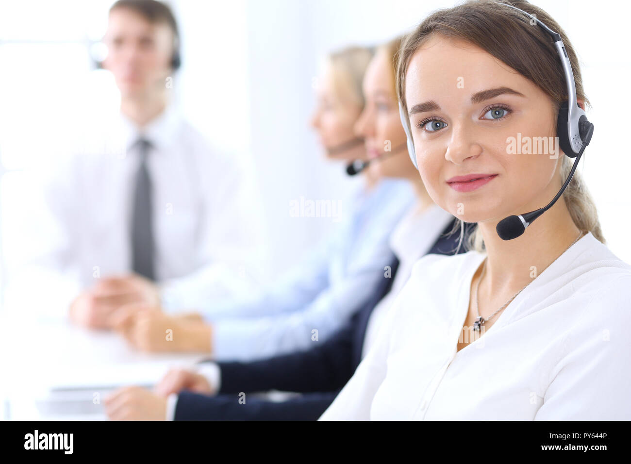 Group of call center operators at work. Focus on beautiful business woman in headset Stock Photo ...