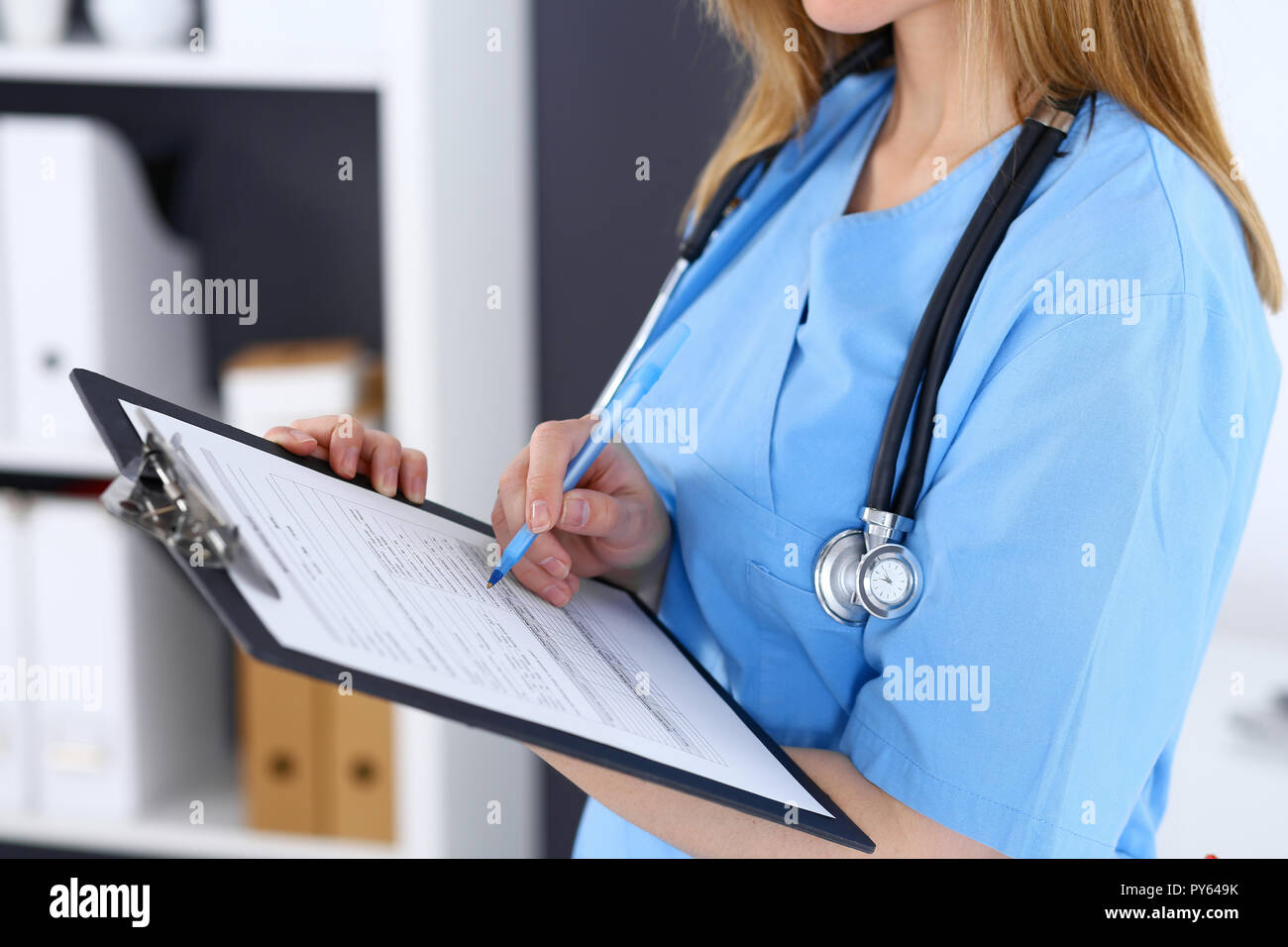 Female doctor filling up medical form on a clipboard, closeup ...