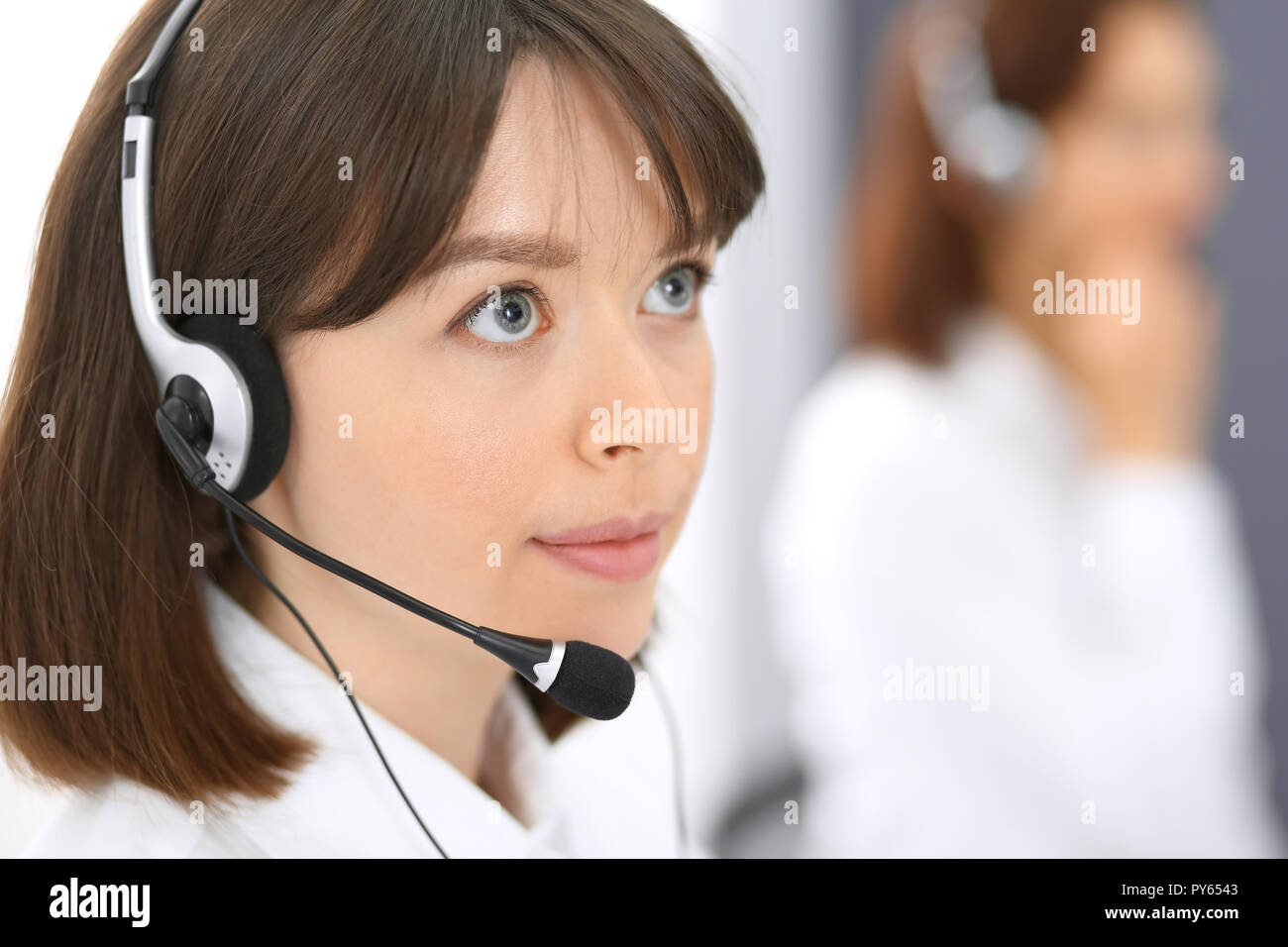 Call center. Group of operators at work. Focus on young brunette woman. Business concept Stock ...