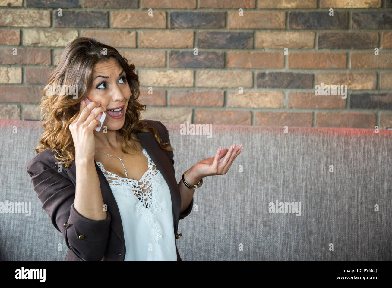 Beautiful young woman explaining something on the phone while looking ...