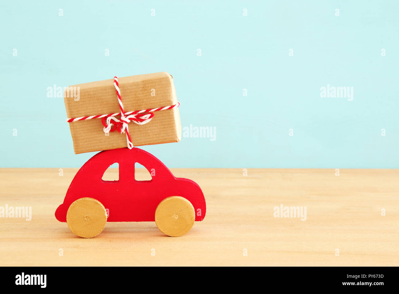 Wooden red car carrying a christmas gift Stock Photo - Alamy