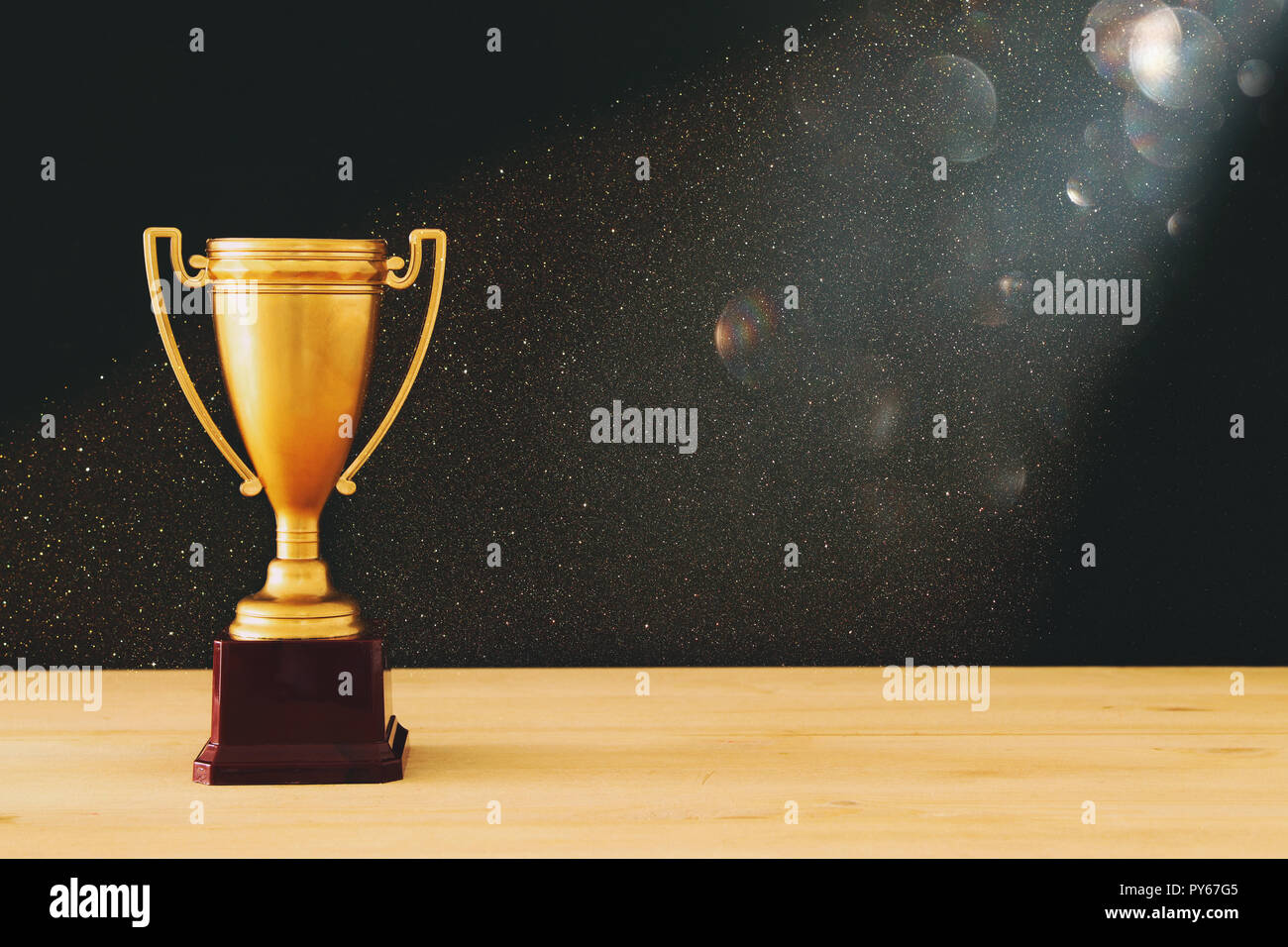 low key image of gold trophy over wooden table and dark background ...