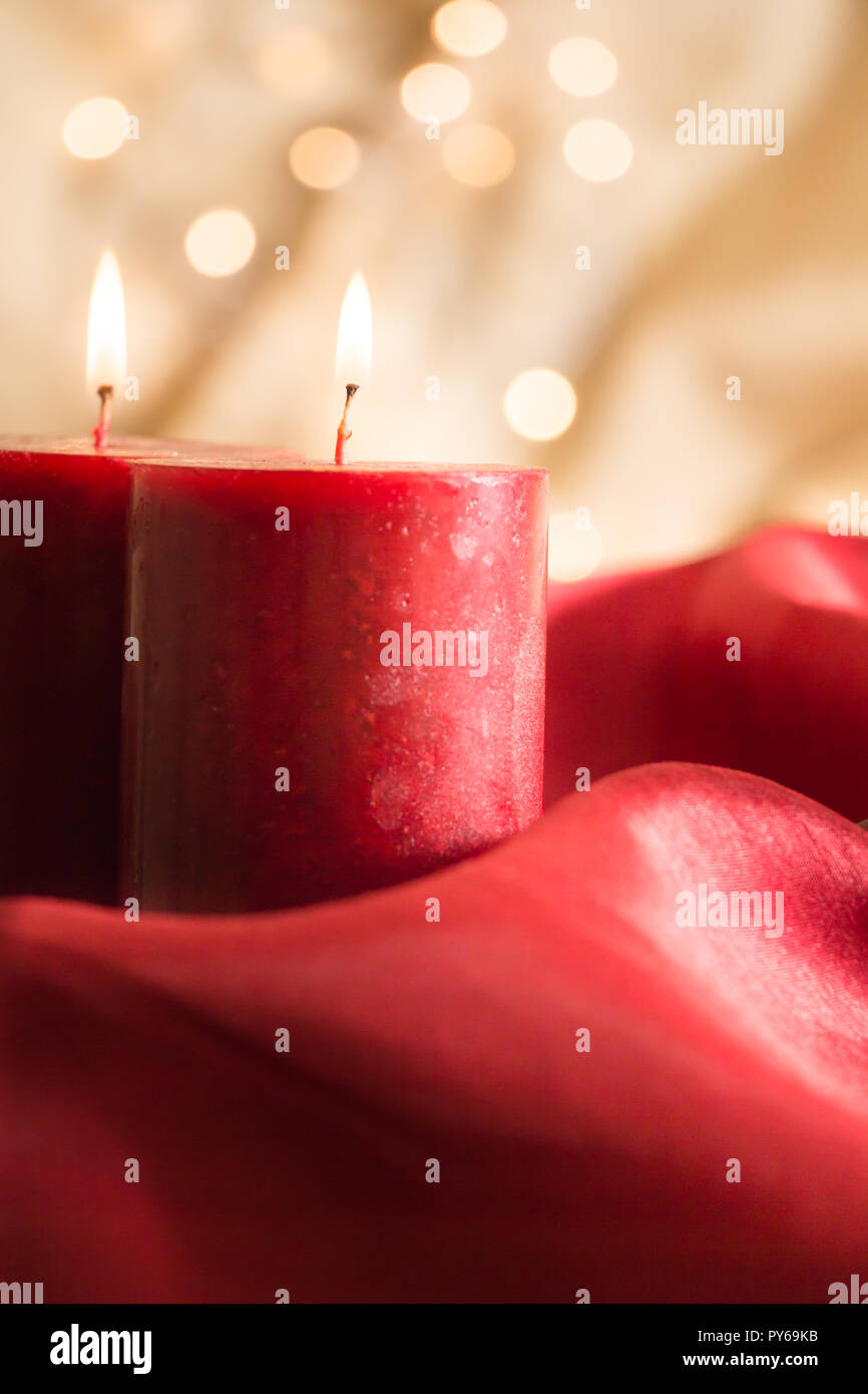 Lit red candles , on red wavy fabric and golden background with bokeh ...