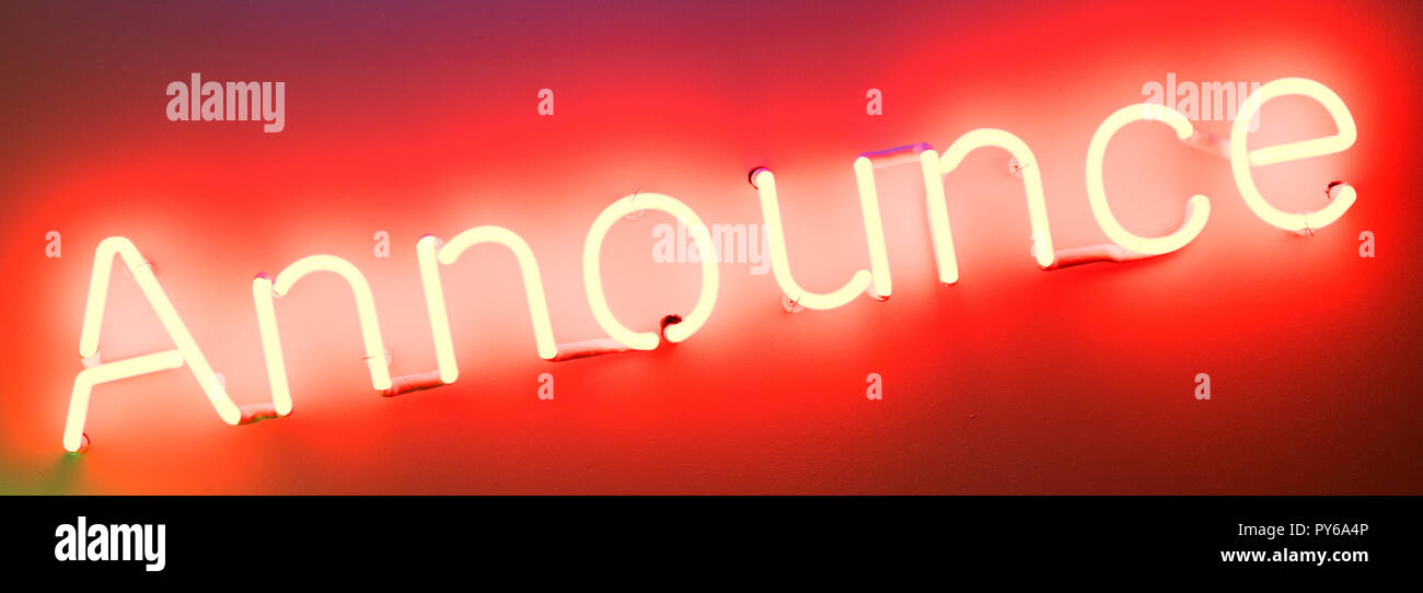 Neon sign - Shining over a white wall - Announce Stock Photo - Alamy