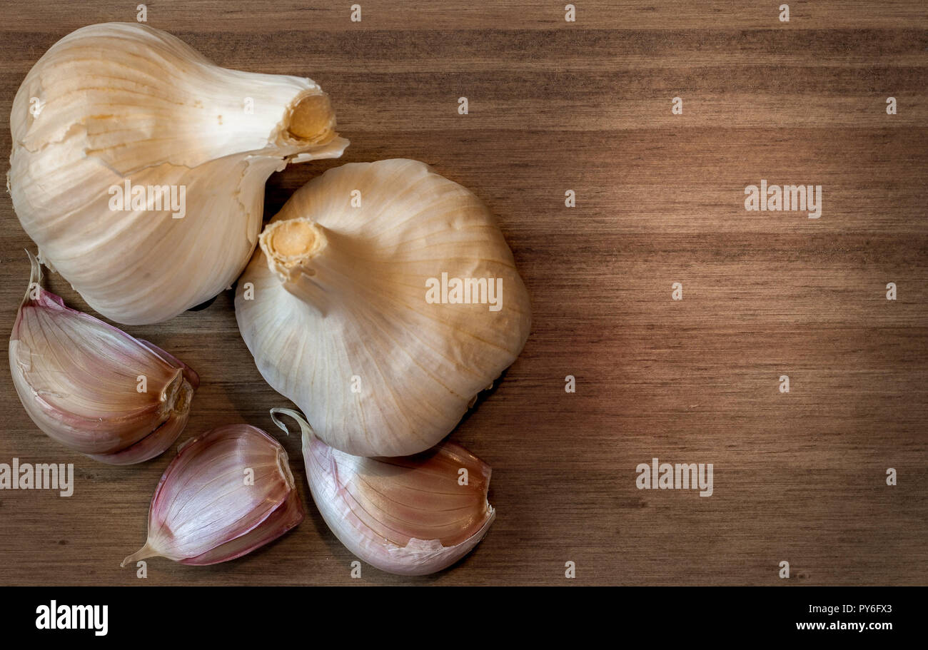 Top view of two whole garlic heads and loose garlic cloves on wooden ...