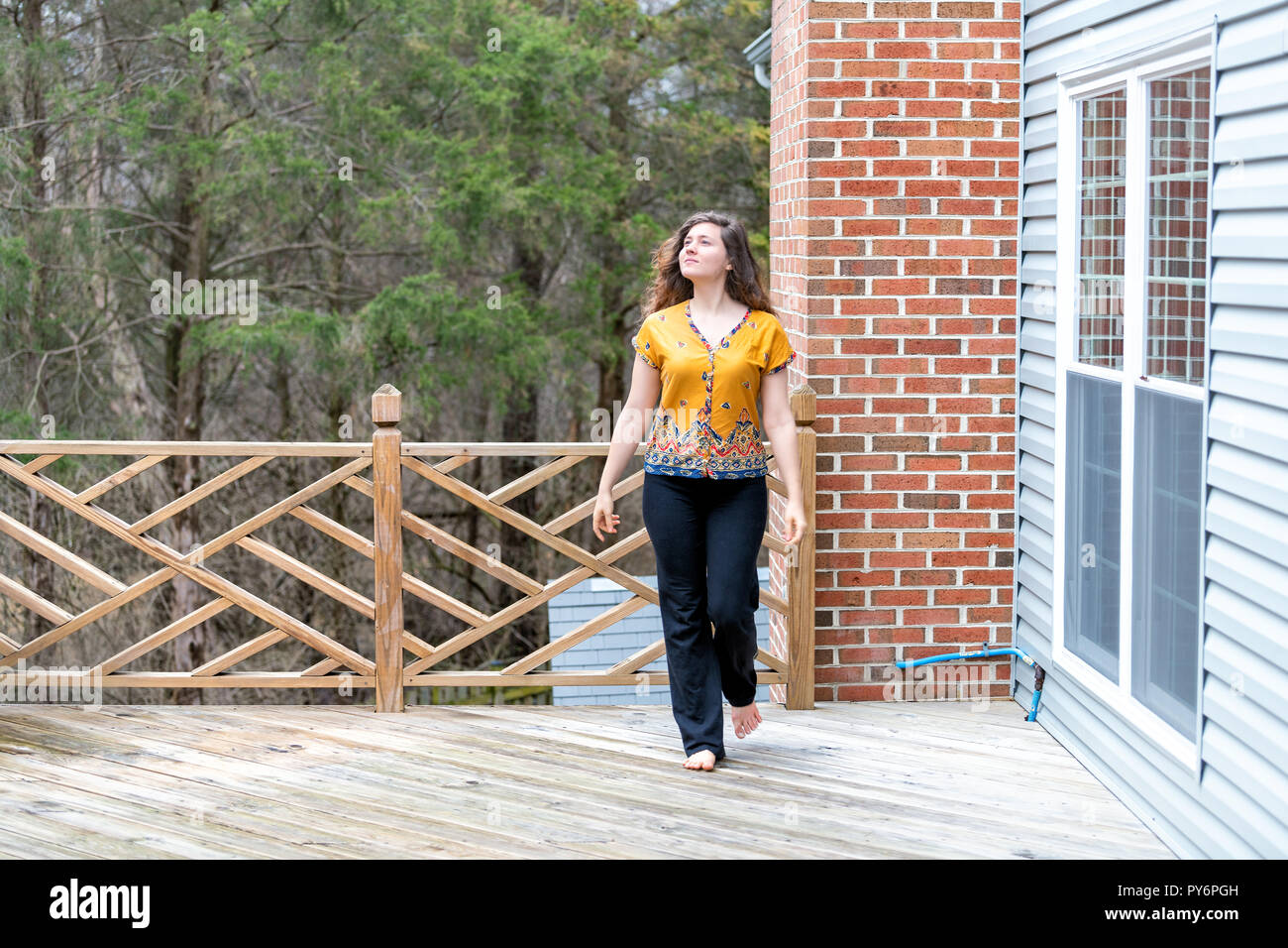 One young woman walking outside, outdoors barefoot on wooden house ...