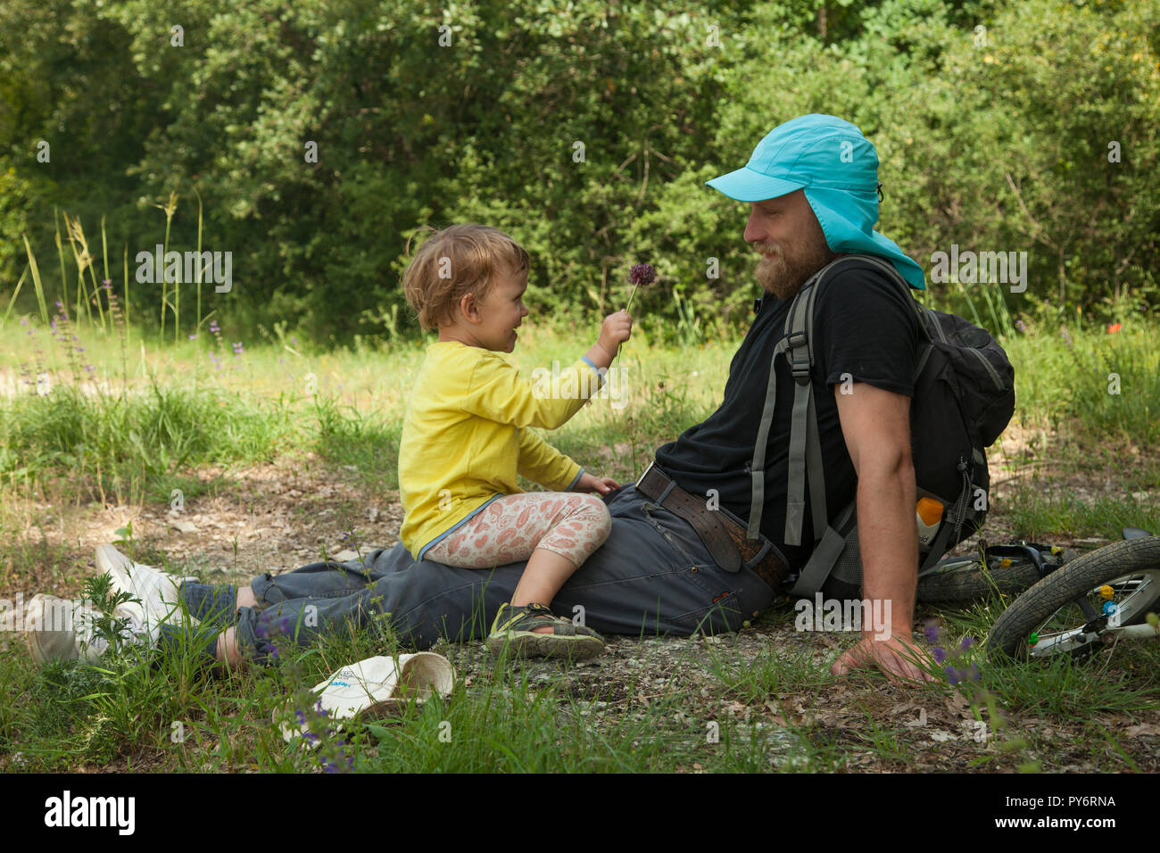 Little girl with her father sniffing a flower and smiling laughing out ...