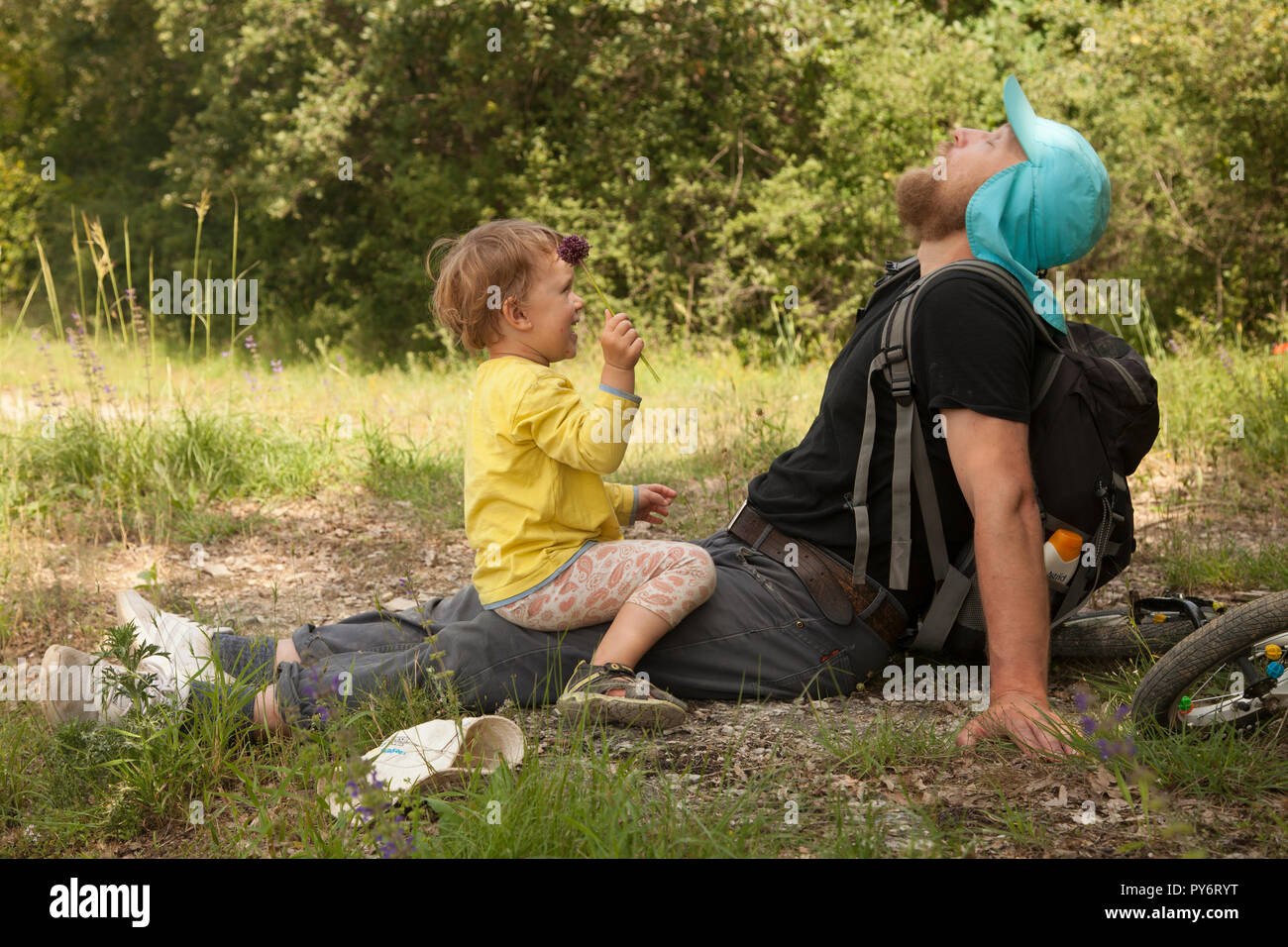 Little girl with her father sniffing a flower and smiling laughing out ...