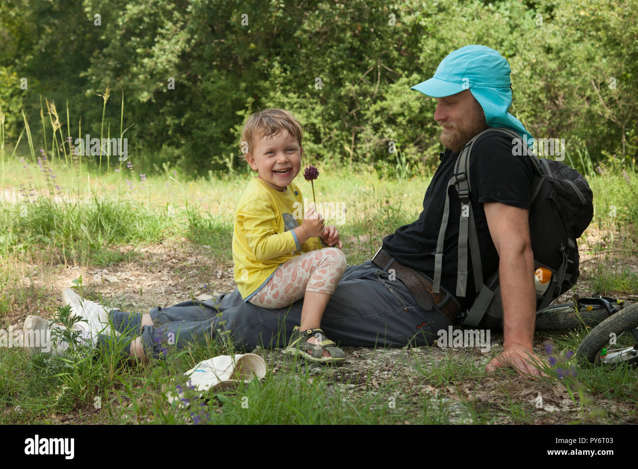 Little girl with her father sniffing a flower and smiling laughing out ...