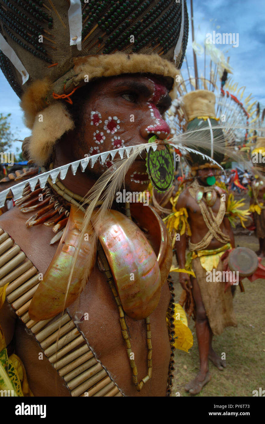 Colourfully dressed and face painted man with shell necklace as part of ...