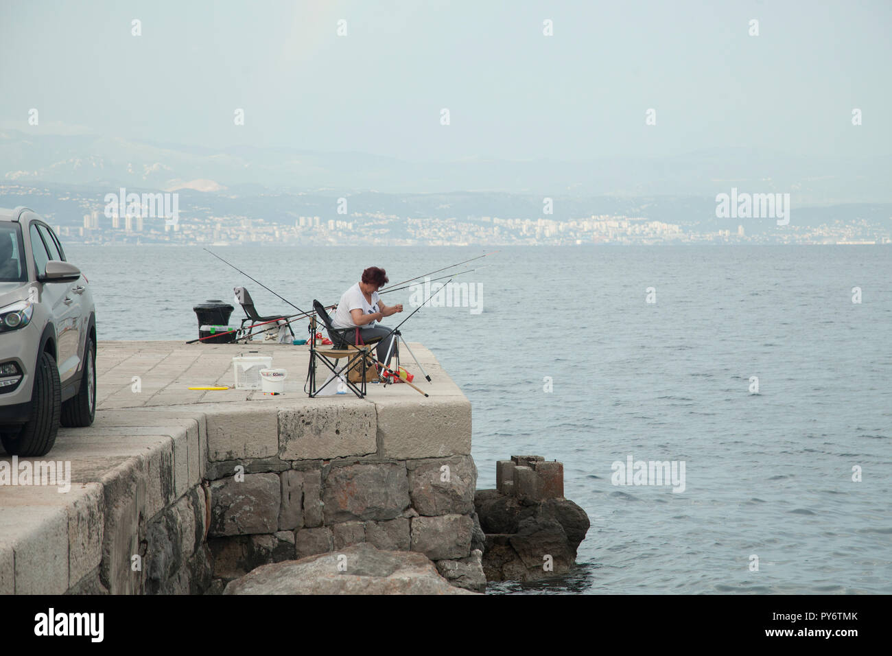 Side View Of Woman Fishing On Pier in sea water on sunny day Stock ...