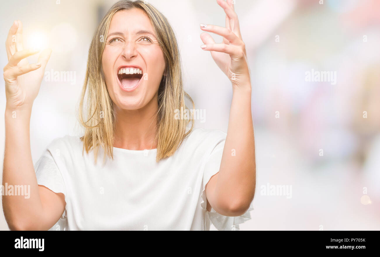 Young beautiful woman over isolated background crazy and mad shouting ...