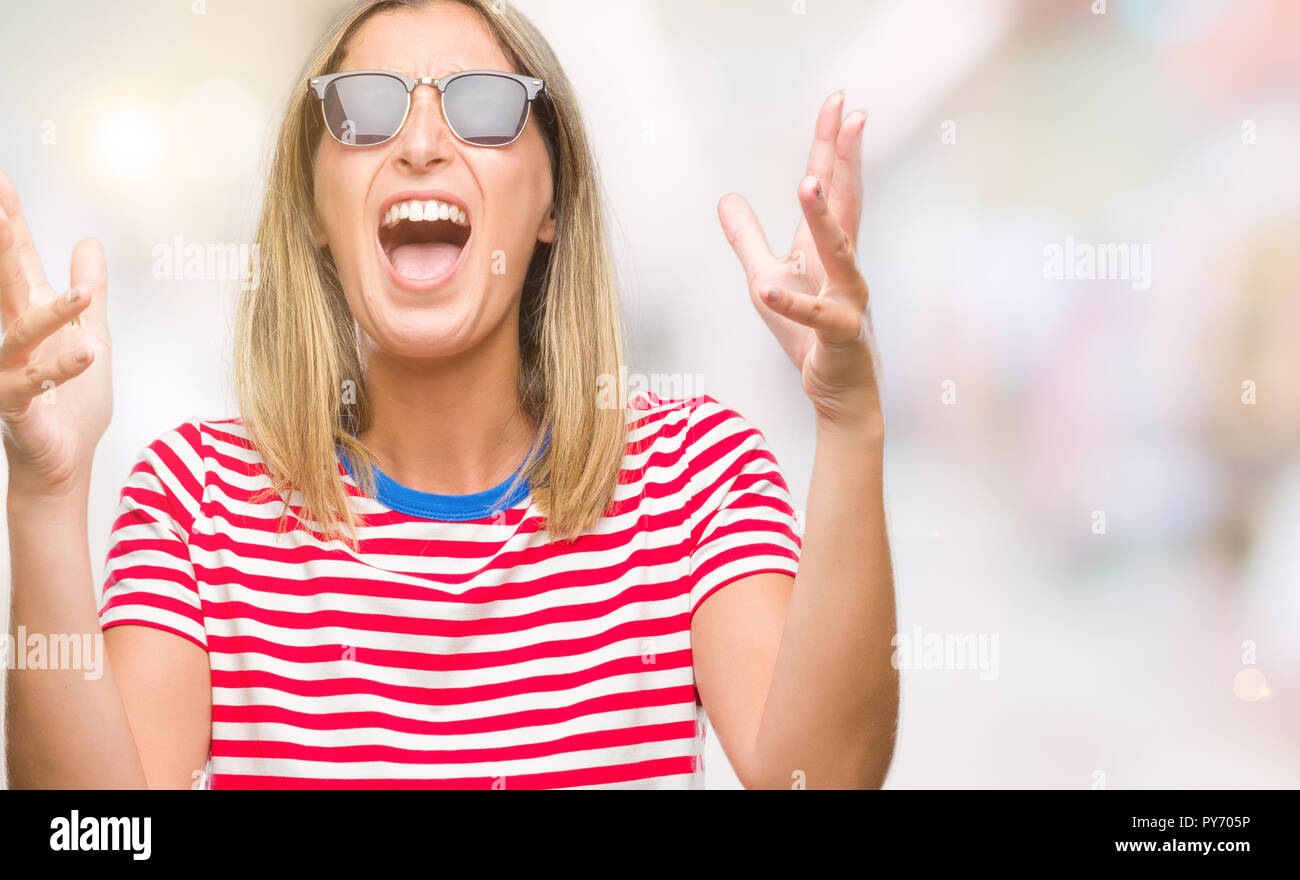 Young beautiful woman wearing sunglasses over isolated background crazy ...