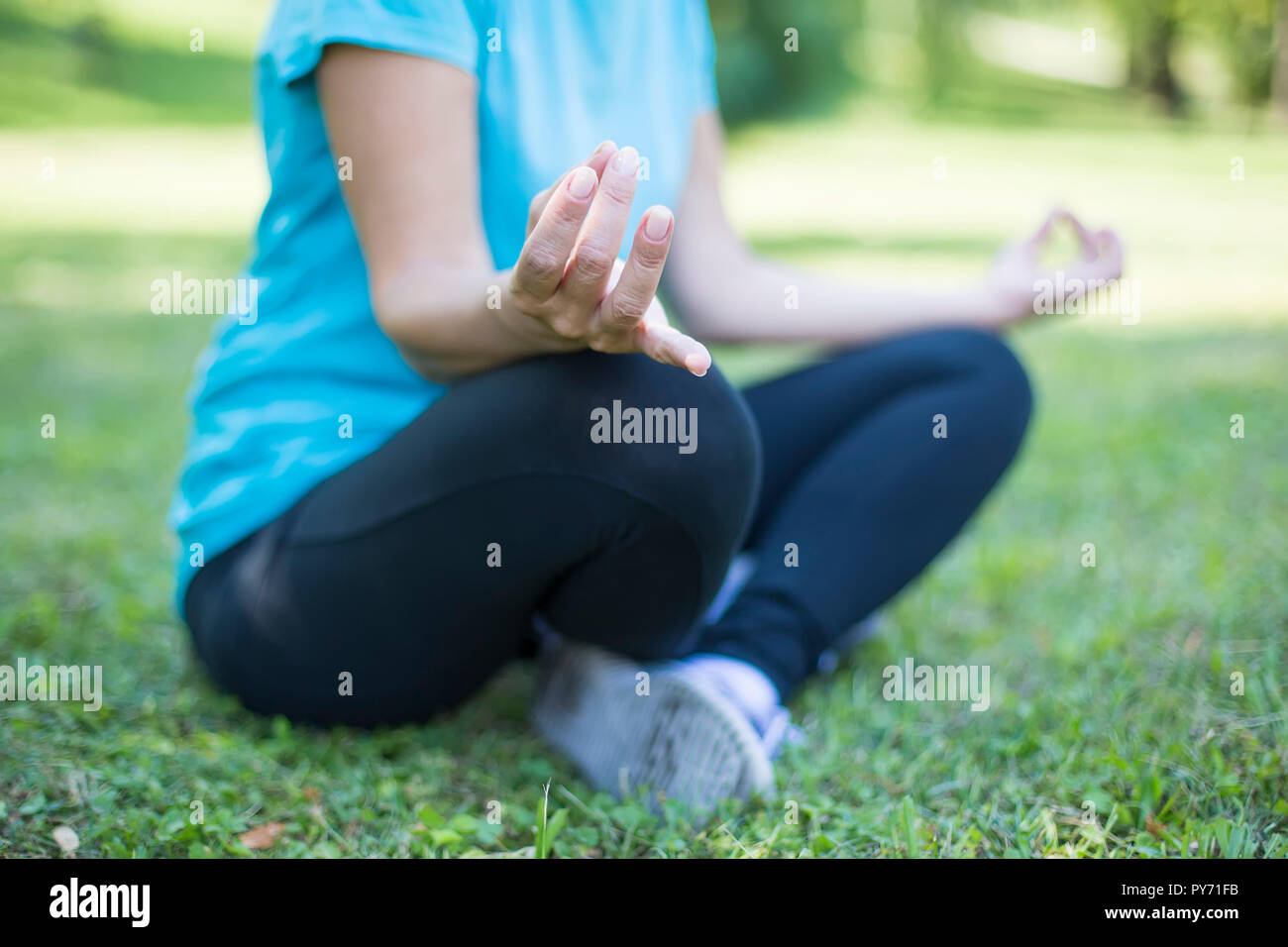 Senior woman in a lotus position on a grass in park Stock Photo - Alamy
