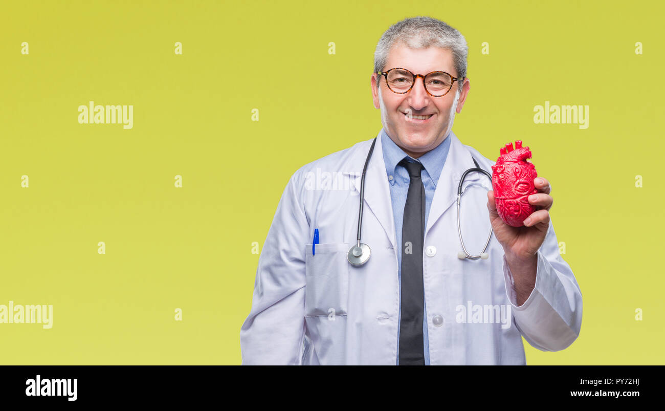 Handsome senior cardiologist doctor man holding heart over isolated ...