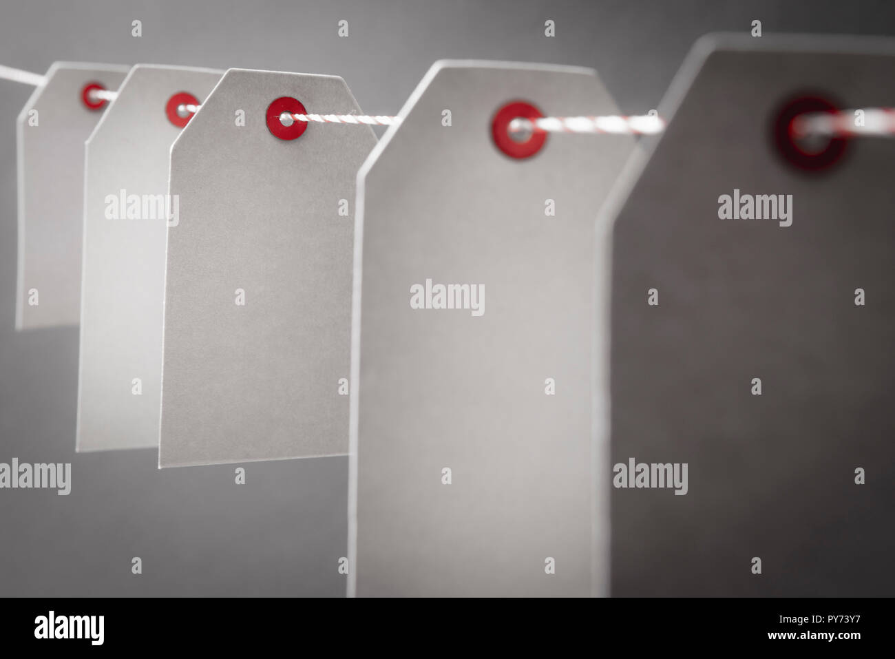 Close up with empty white paper labels lined up on a string on a gray ...