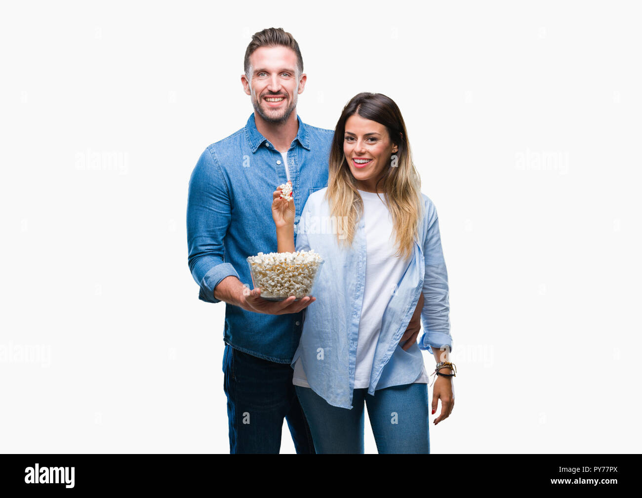 Young couple in love eating popcorn over isolated background with a ...