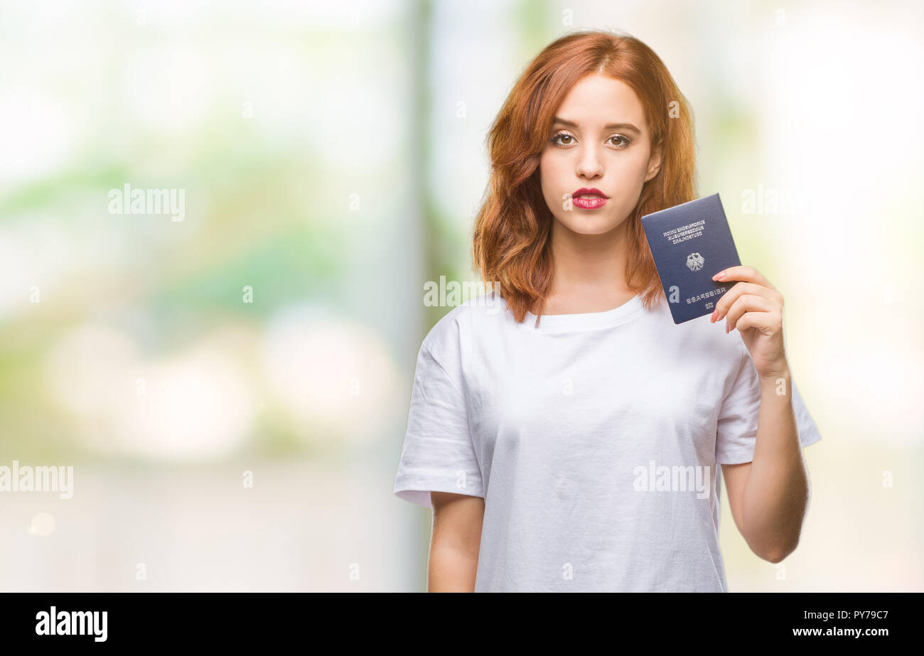 Young beautiful woman holding passport of germany over isolated ...