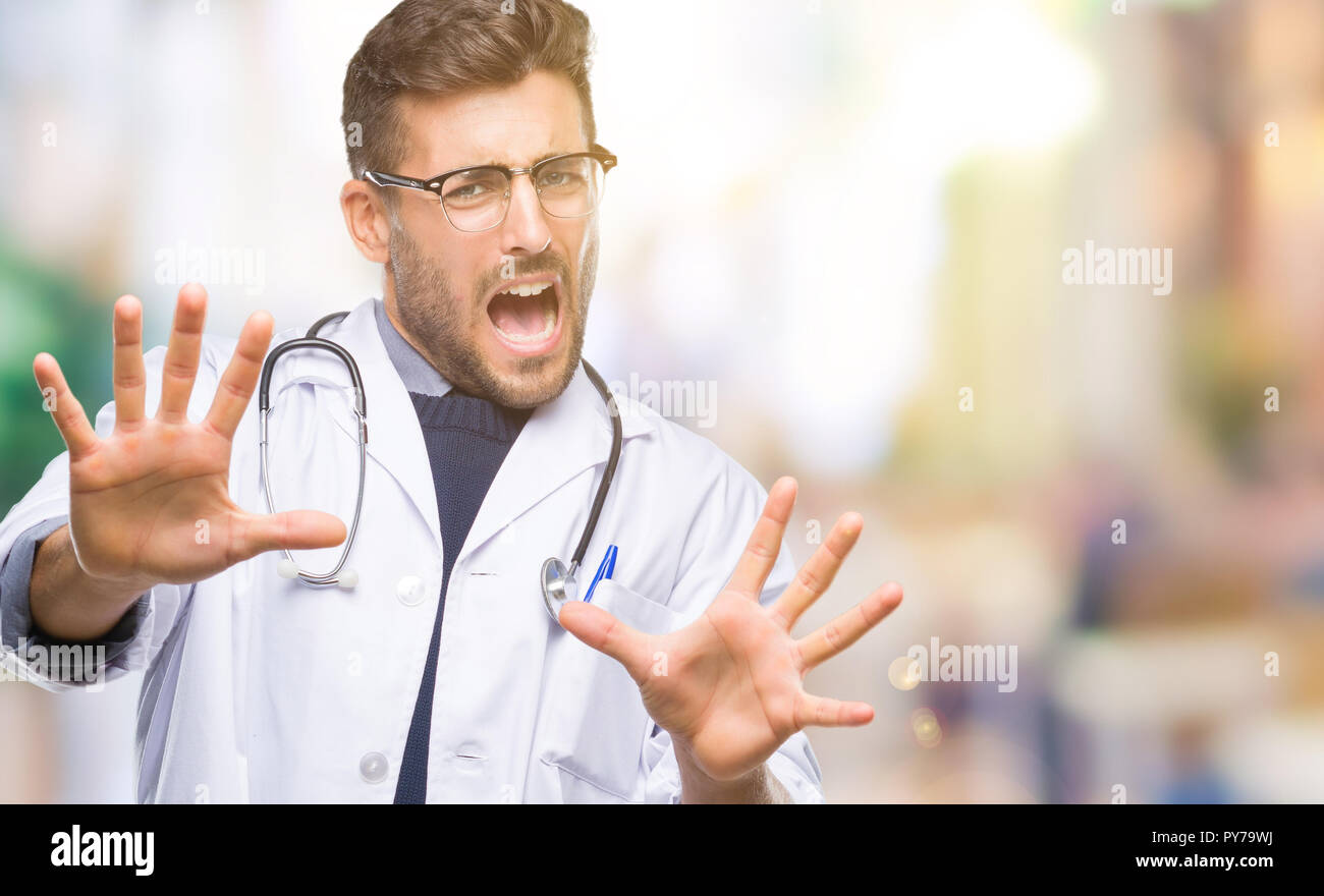 Young handsome doctor man over isolated background afraid and terrified ...