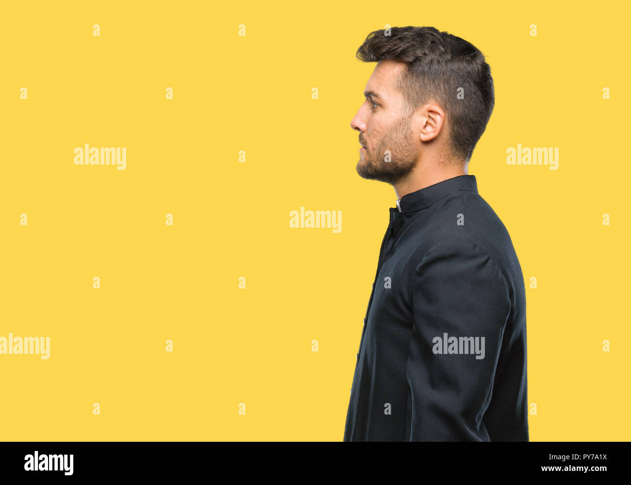 Young catholic christian priest man over isolated background looking to ...