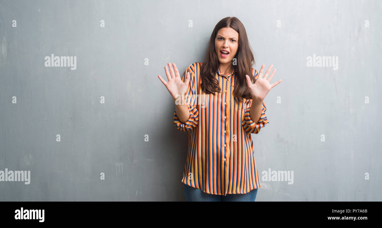 Young brunette woman over grunge grey wall afraid and terrified with ...