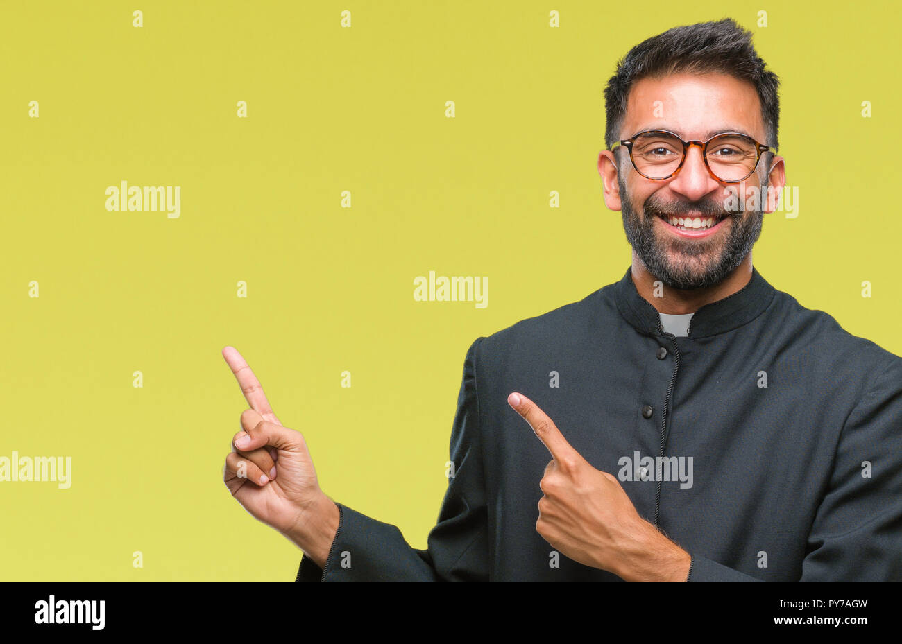 Adult hispanic catholic priest man over isolated background smiling and ...
