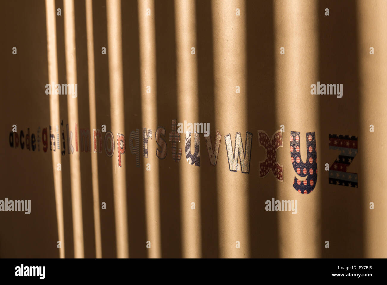 Alphabet letters on wall with light shining through blinds onto wall ...