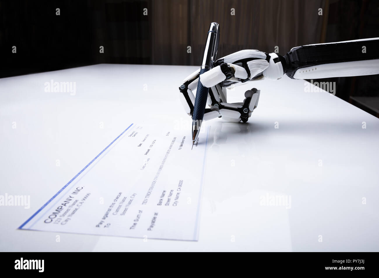 Robotic Hand Signing Cheque With Pen On Desk Stock Photo - Alamy