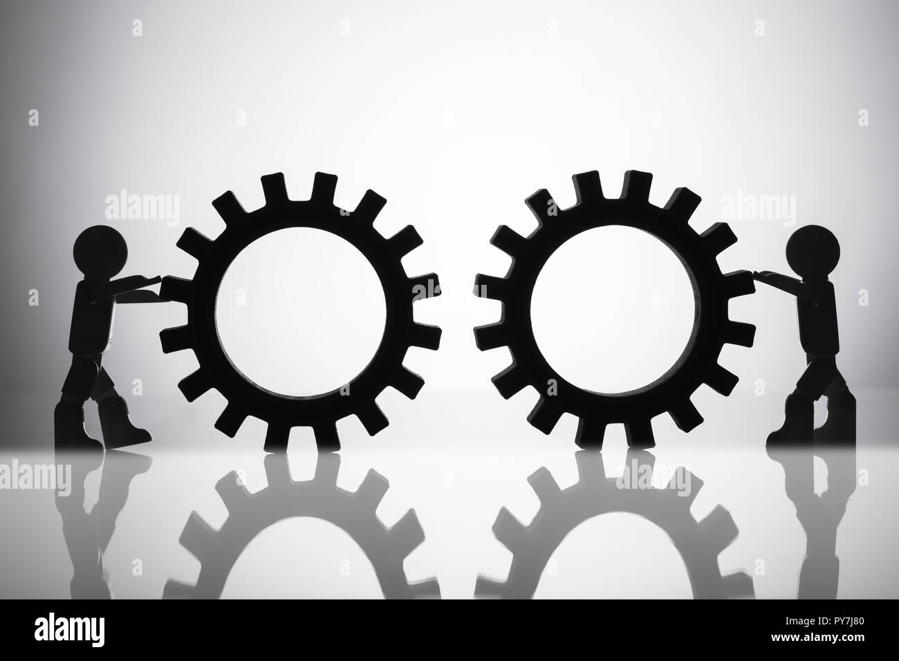 Silhouette Of Two Human Figure Connecting Gears On Reflective ...