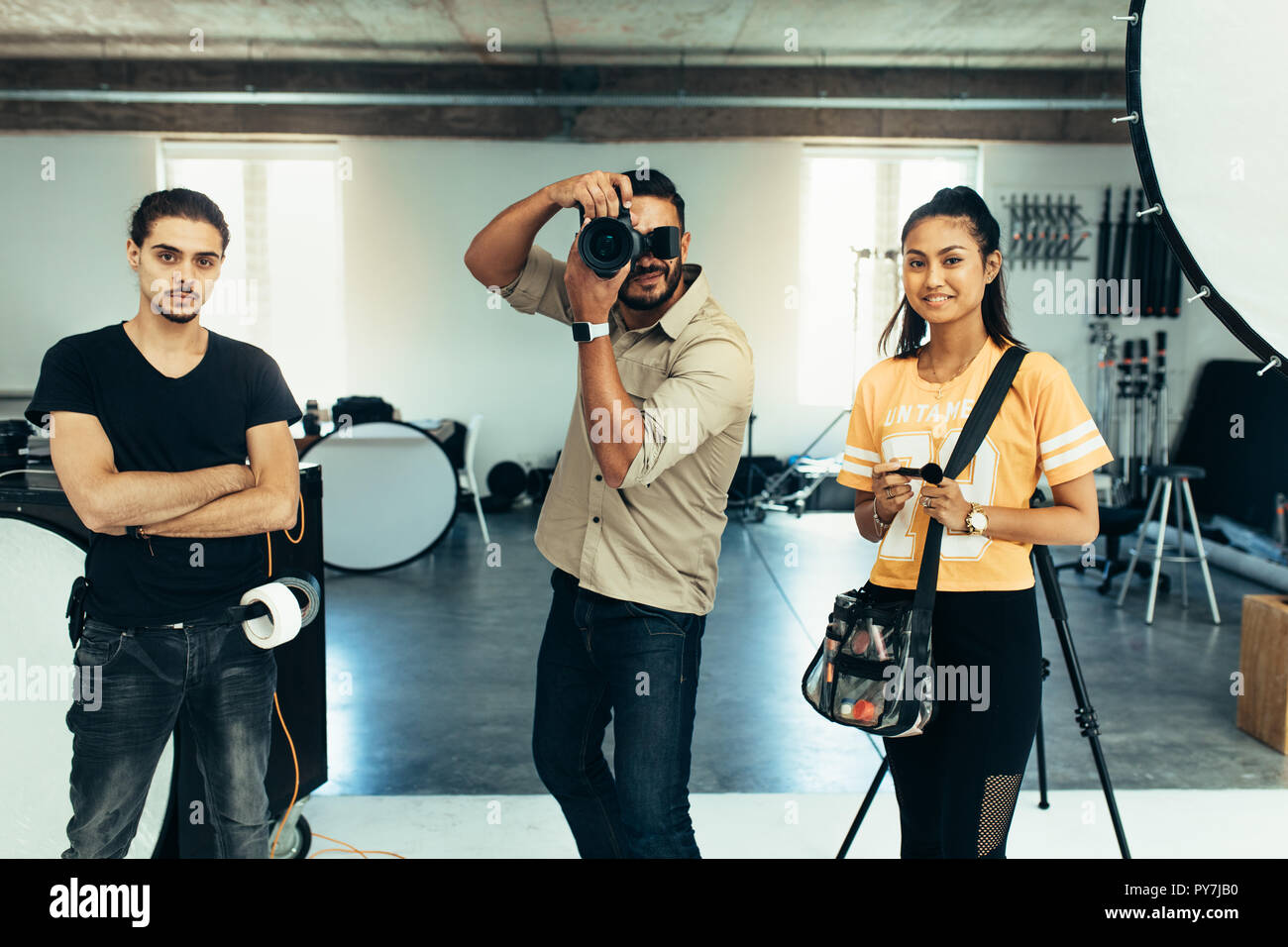 Photographer taking photos in a studio with his crew standing beside ...