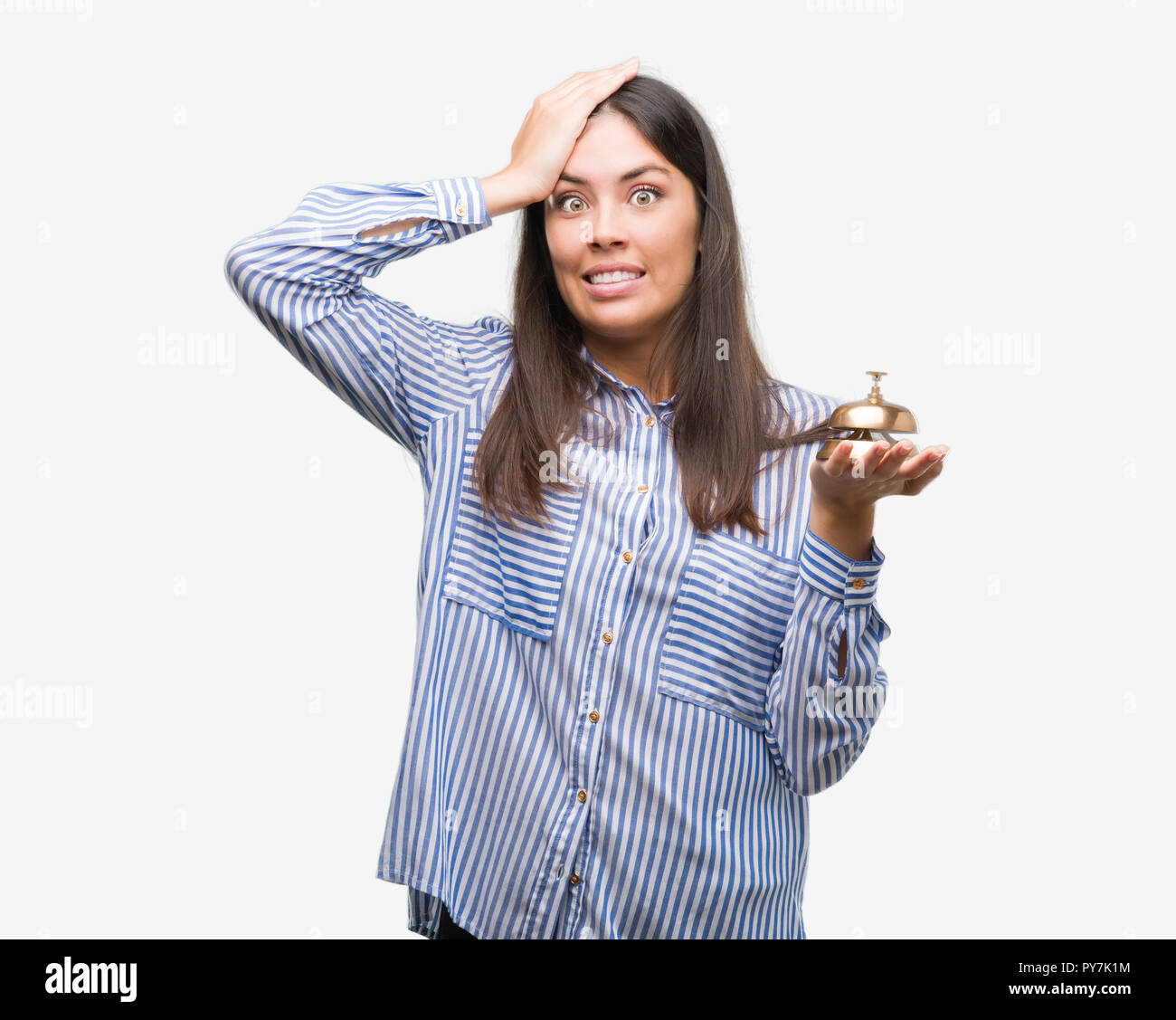 Young beautiful hispanic holding hotel ring bell stressed with hand on ...