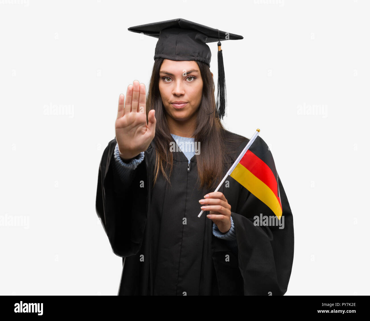 Young hispanic woman wearing graduated uniform holding flag of germany ...