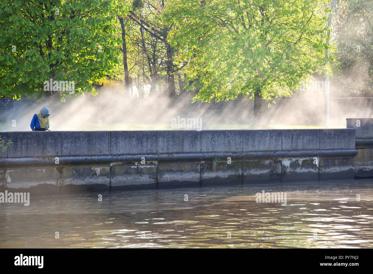 Worker removes dirt from the parapet on the embankment of the Pregolya ...