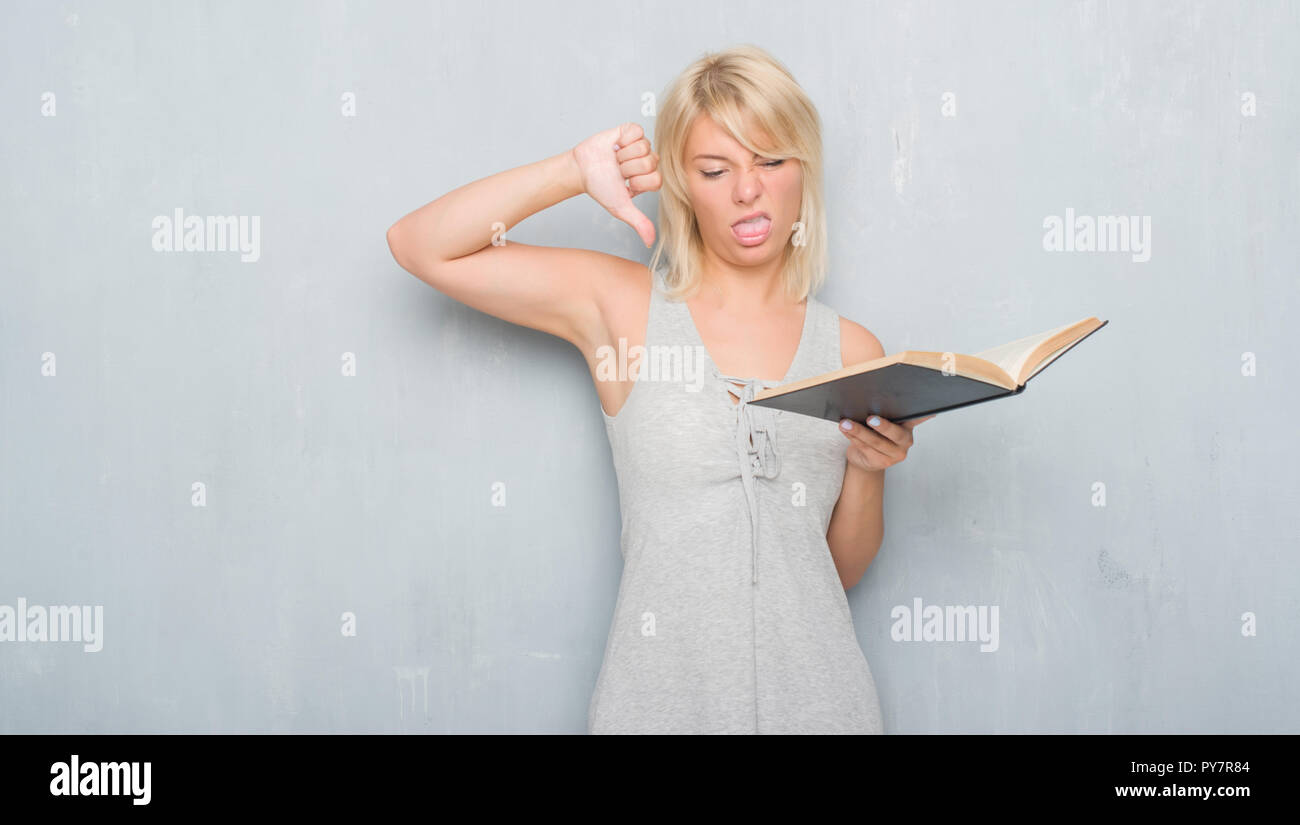 Caucasian adult woman over grey grunge wall reading a book with angry ...
